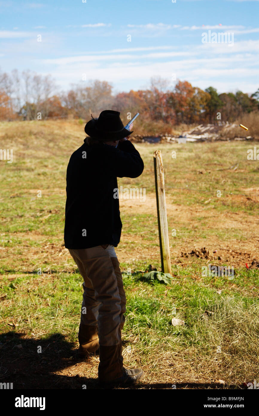 Hunter firing shotgun at clays Shell flying out of gun Stock Photo - Alamy