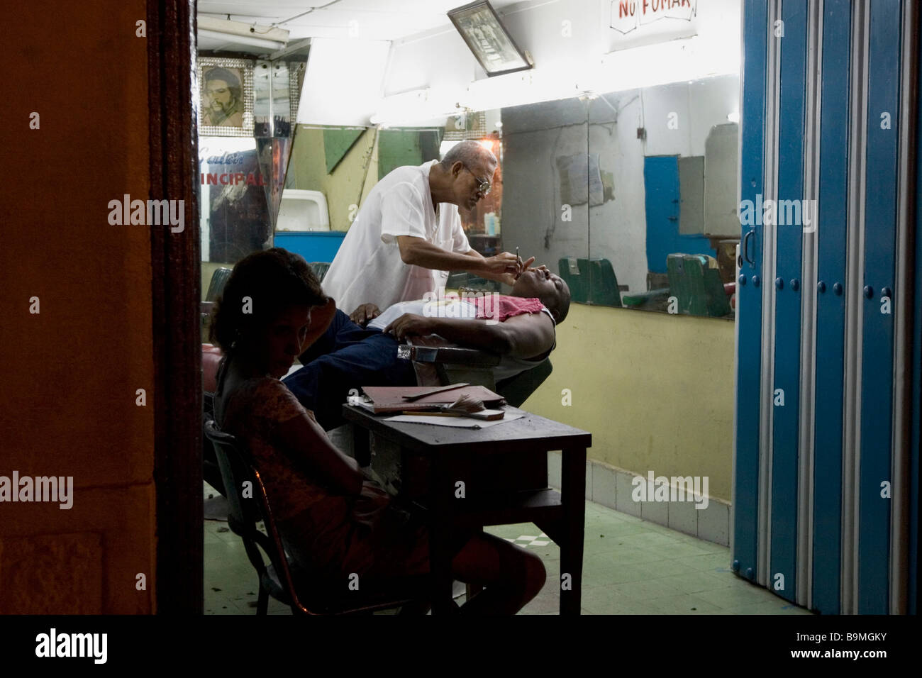 A barber giving a customer a wet shave in a barber shop in Santiago de ...