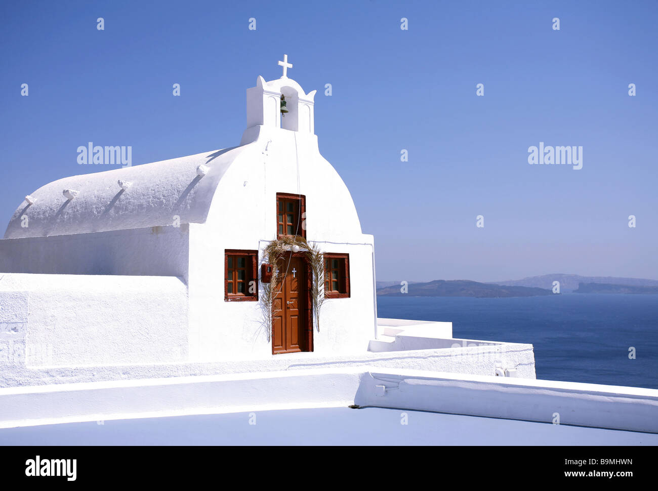 An orthodox greek chapel,in Oia on Santorini,against a bright blue sky ...