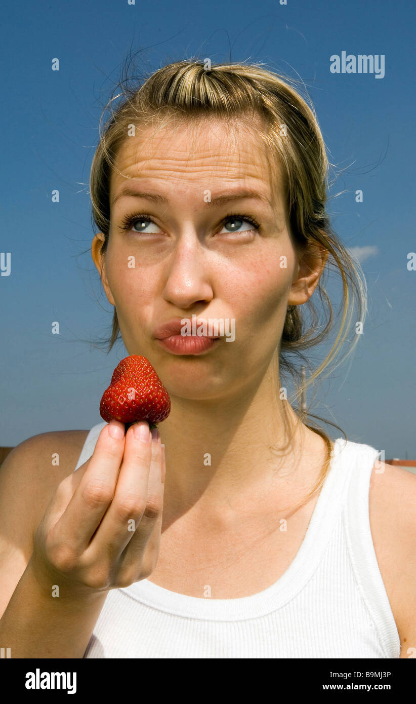 Young woman eating a strawberry Stock Photo - Alamy