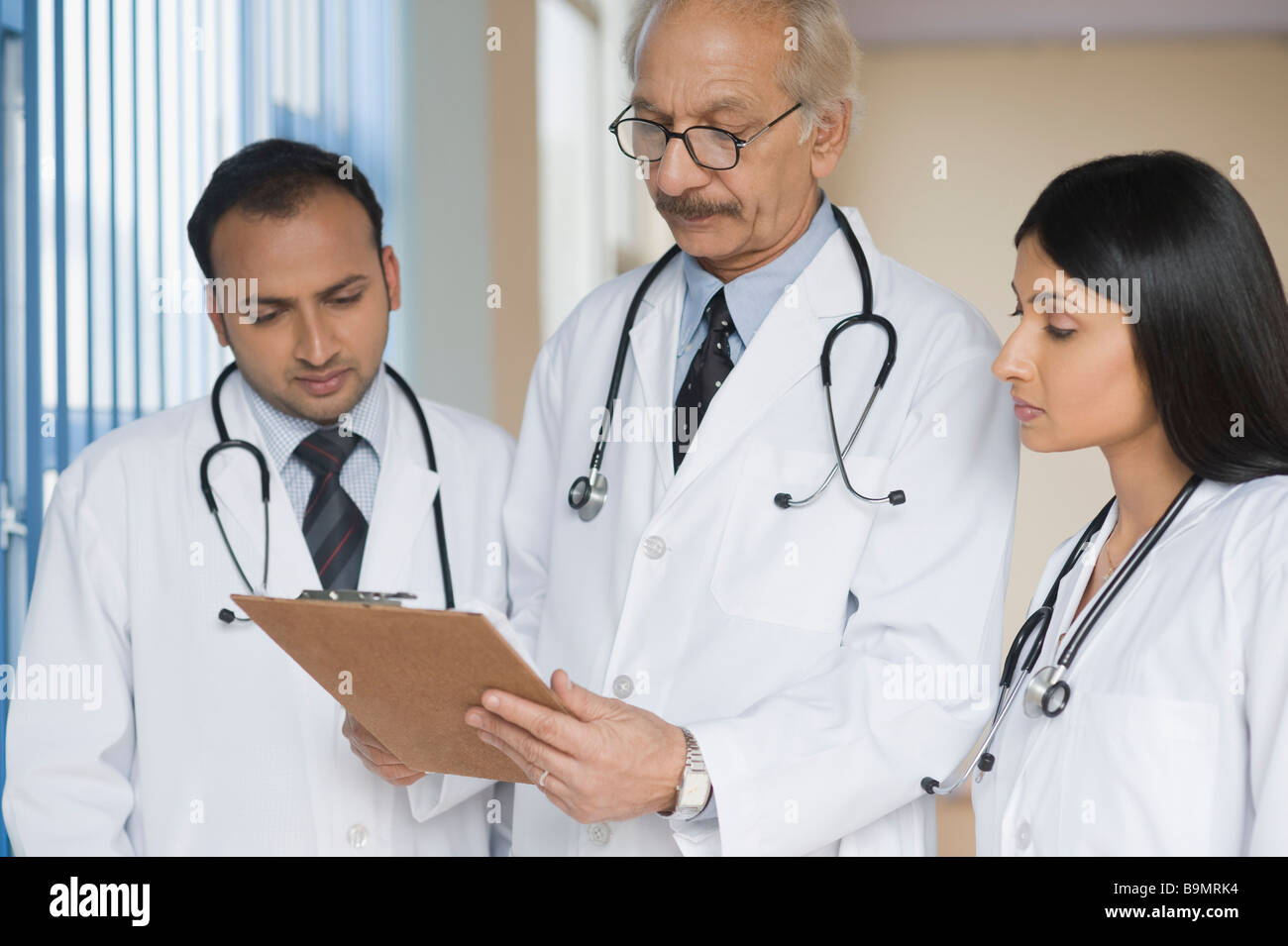 Three doctors examining a report Stock Photo - Alamy
