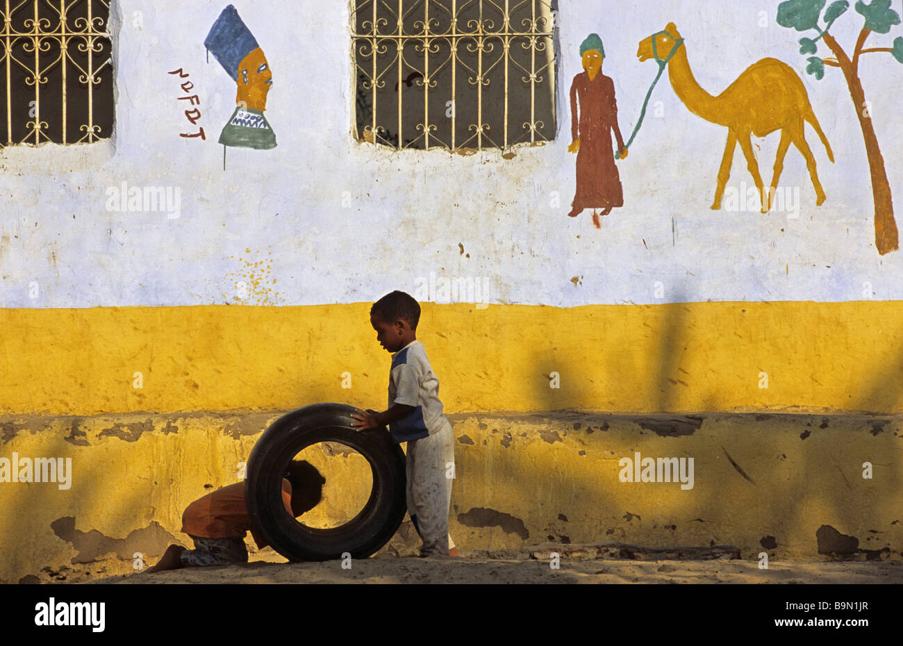 Egypt, Upper Egypt, Aswan, Nubian child playing with a tyre in front of ...