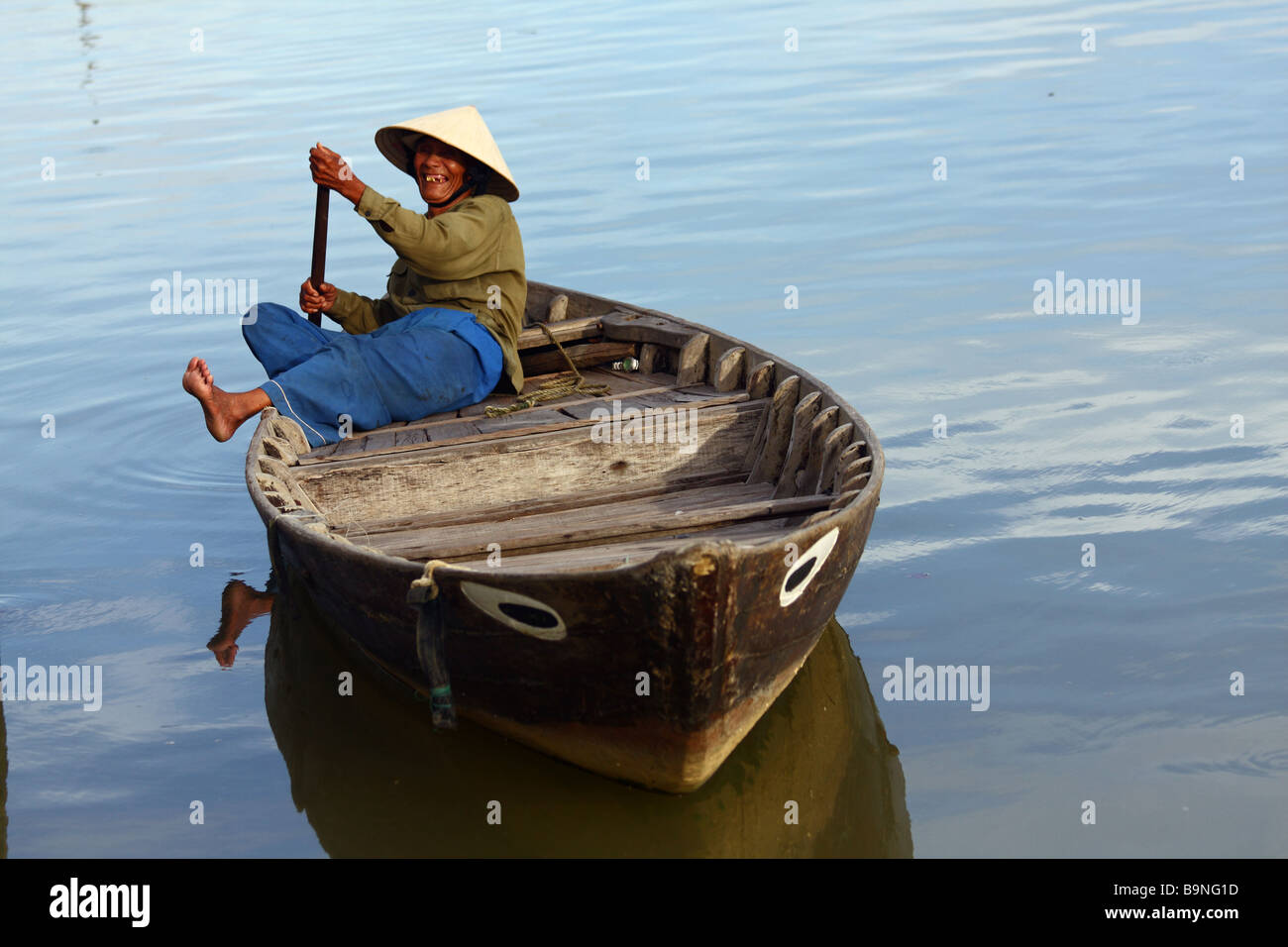 Boatman with the traditional conical hat smiling on his wooden canoe on ...