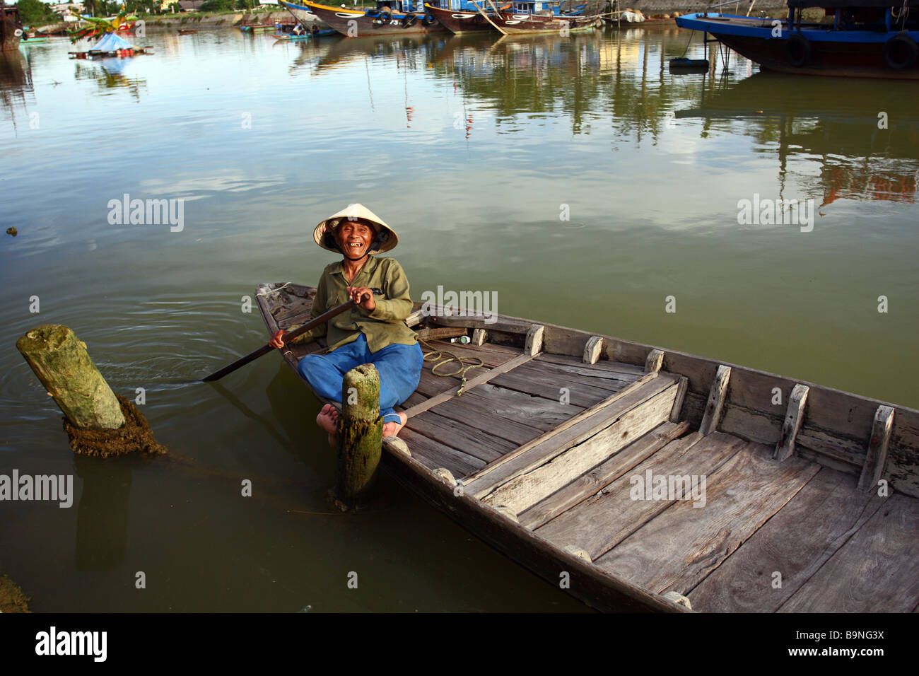Boatman with the traditional conical hat smiling on his wooden canoe on ...