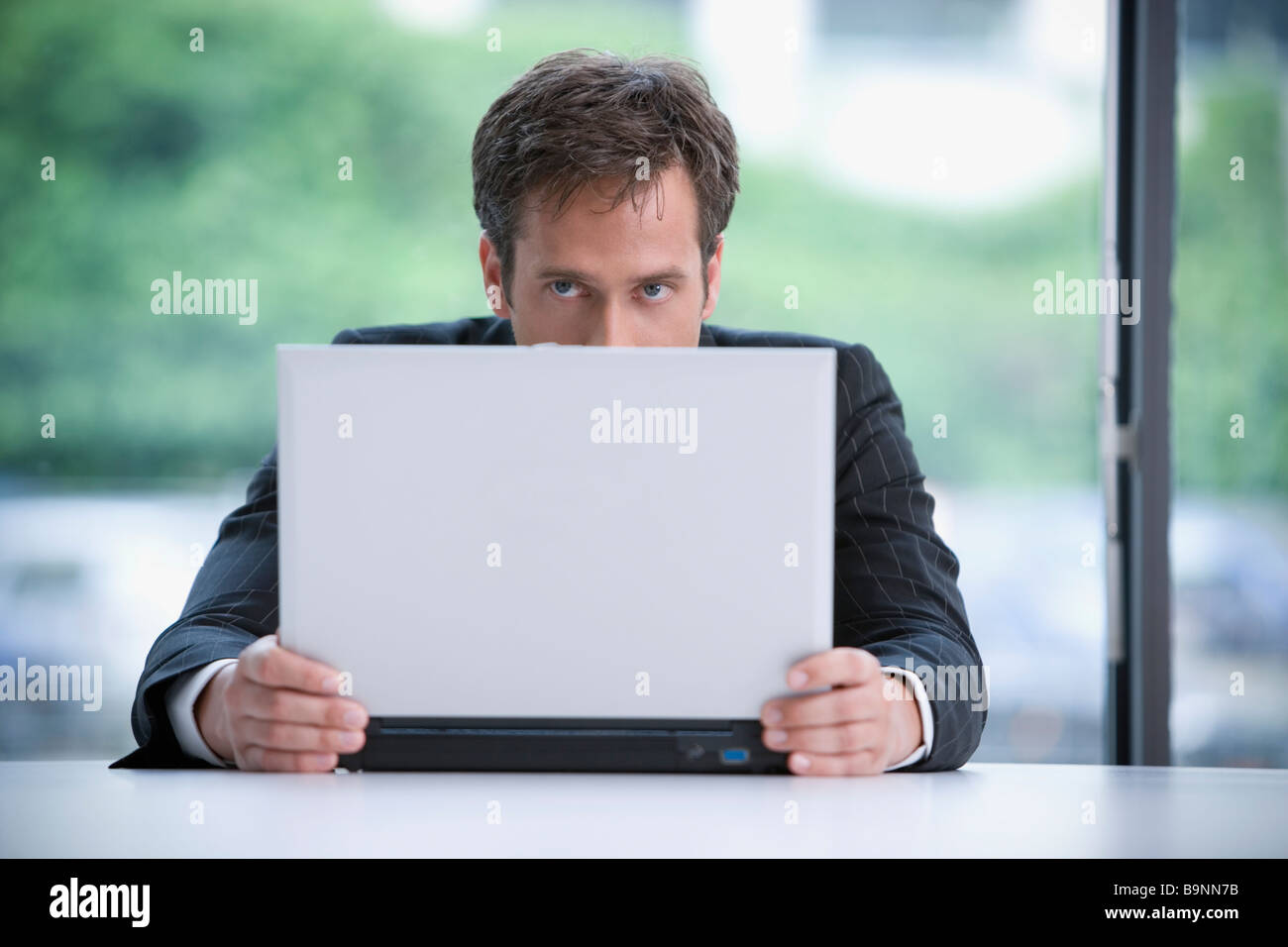 portrait of businessman hiding behind laptop computer Stock Photo - Alamy
