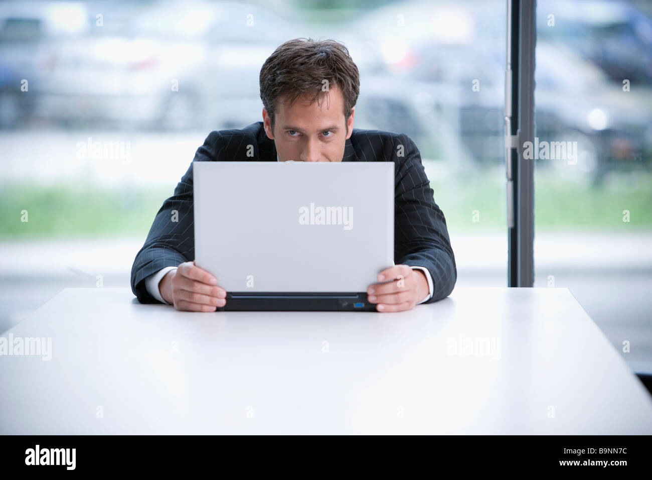 portrait of businessman hiding behind laptop computer Stock Photo - Alamy