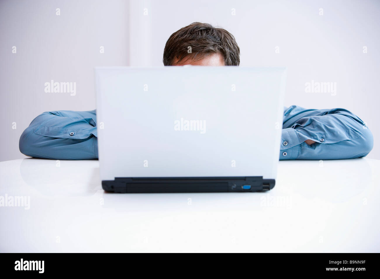 businessman hiding behind laptop computer Stock Photo - Alamy