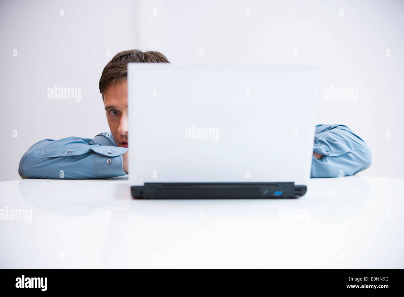 businessman hiding behind laptop computer Stock Photo - Alamy