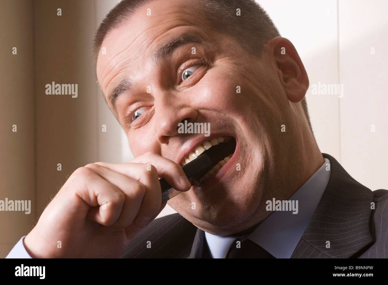 headshot of desperate businessman biting into mobile phone Stock Photo ...