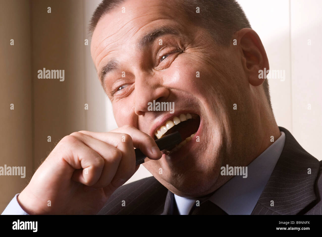 headshot of desperate businessman biting into mobile phone Stock Photo ...