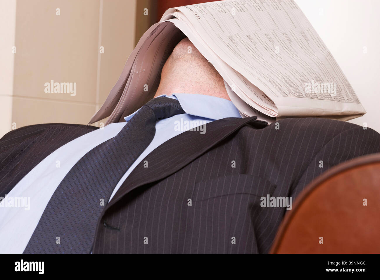 businessman dozing in hotel lobby with newspaper covering his face ...