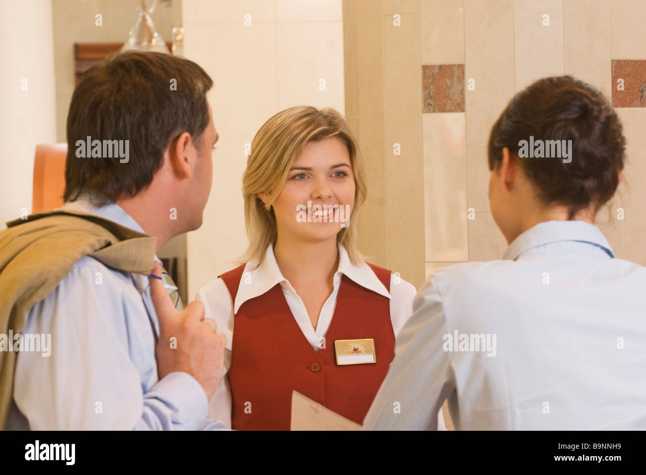 young receptionist talking to hotel guests Stock Photo - Alamy