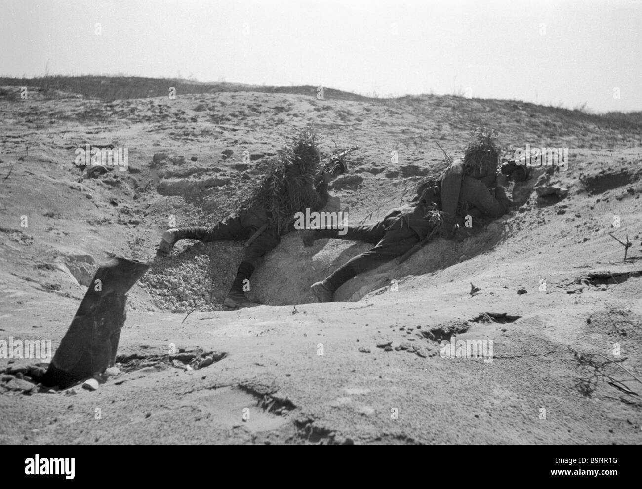 Two soldiers firing submachine guns from a shell hole Stock Photo - Alamy