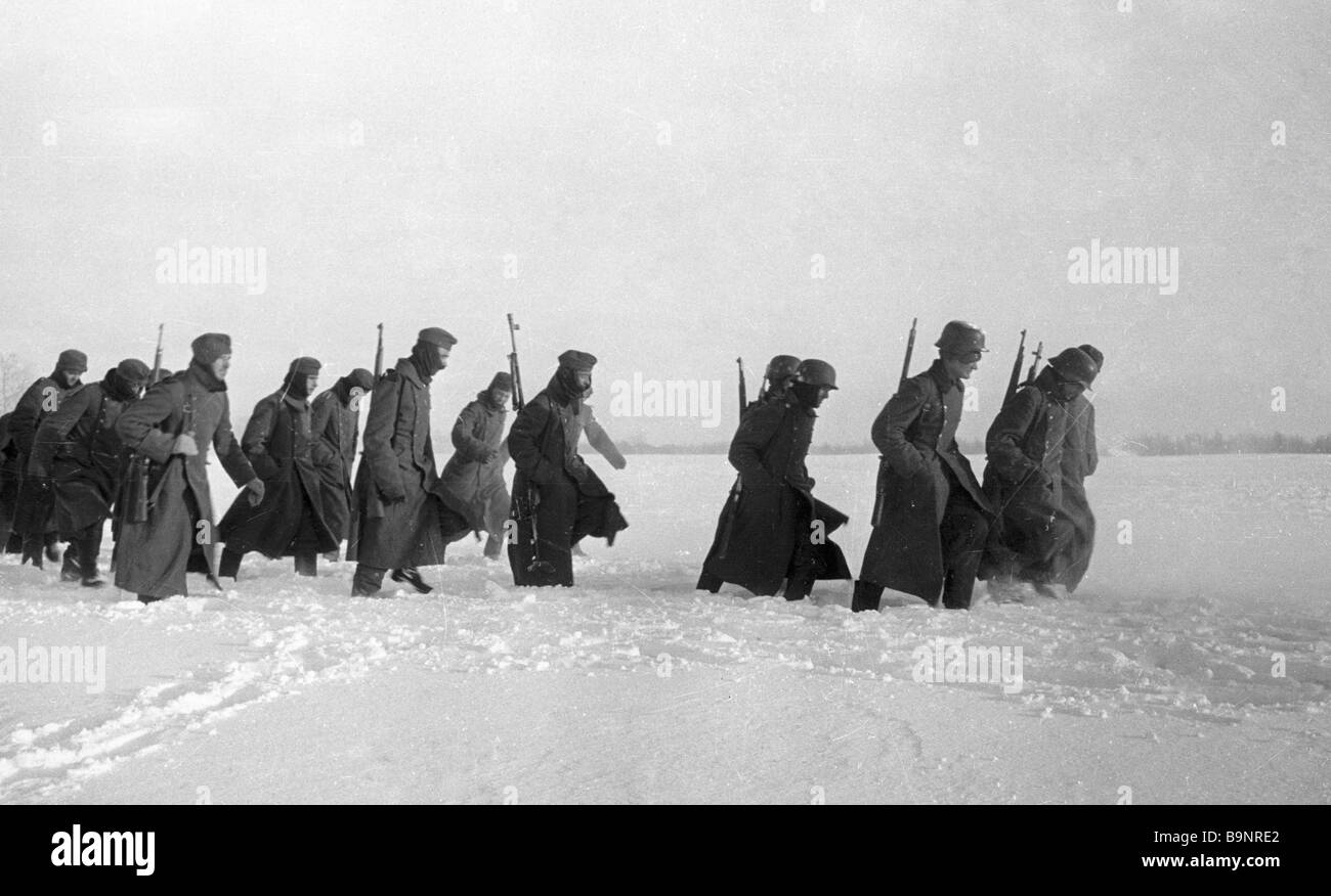The remnants of a defeated Nazi unit walking along a snow covered field ...