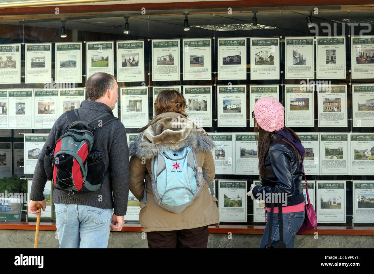 A family looking at houses in an estate agents window Stock Photo - Alamy