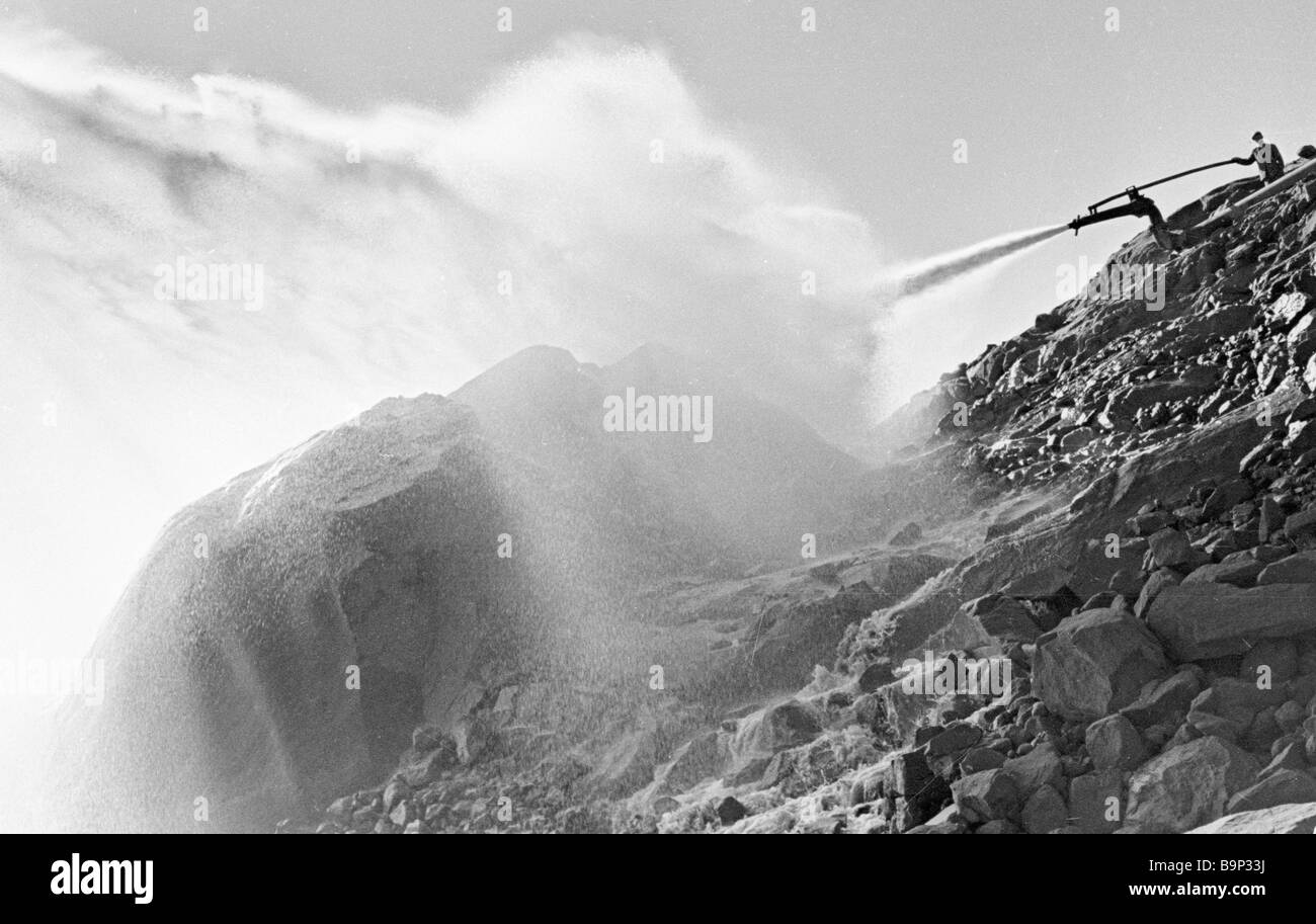 A worker using a hydraulic giant to break rock on the construction of ...