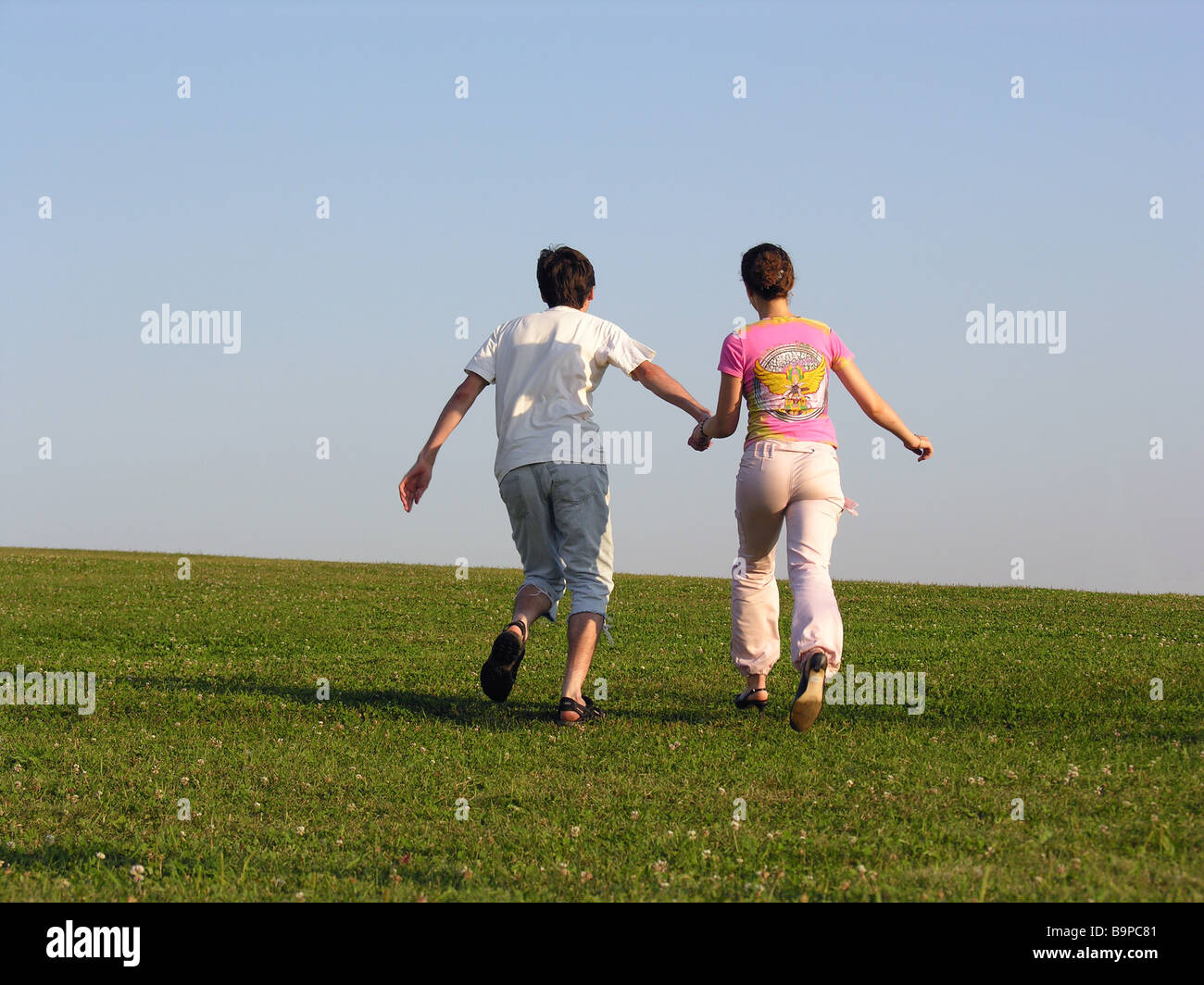 running couple back sky grass Stock Photo - Alamy