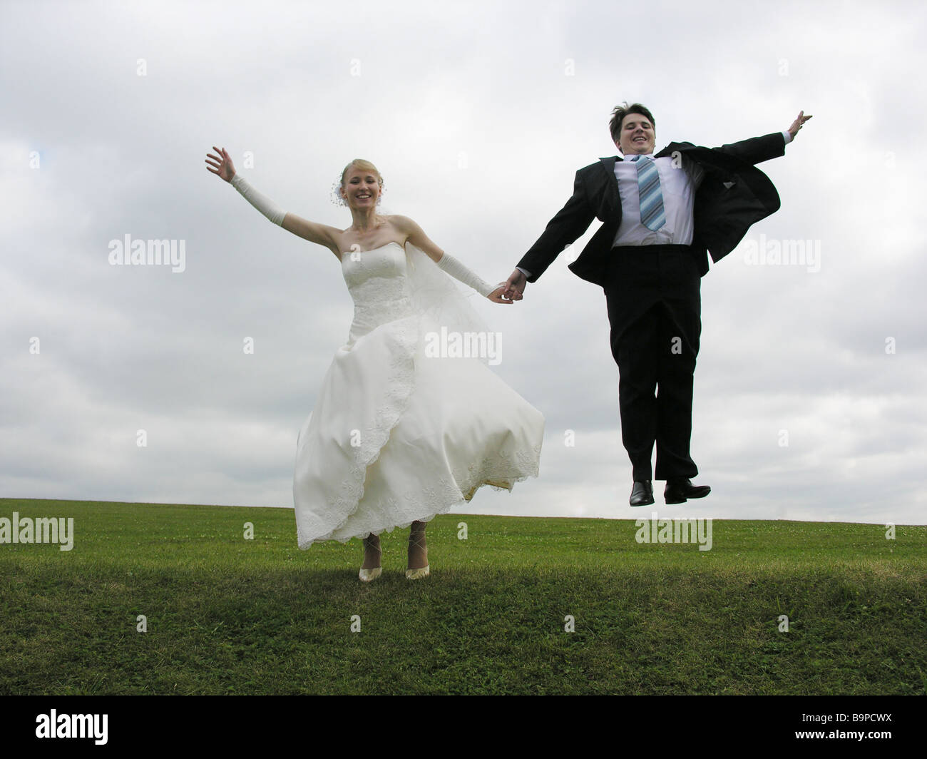 bride and groom jump on meadow Stock Photo - Alamy