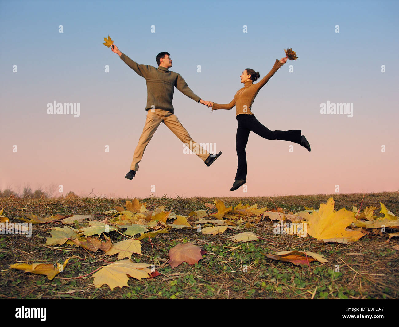 jump couple. autumn leaves. sunset sky Stock Photo - Alamy