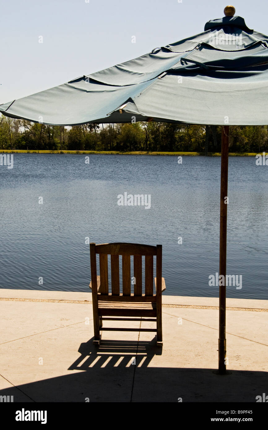 Lounge chair under parasol at lakeside Stock Photo - Alamy