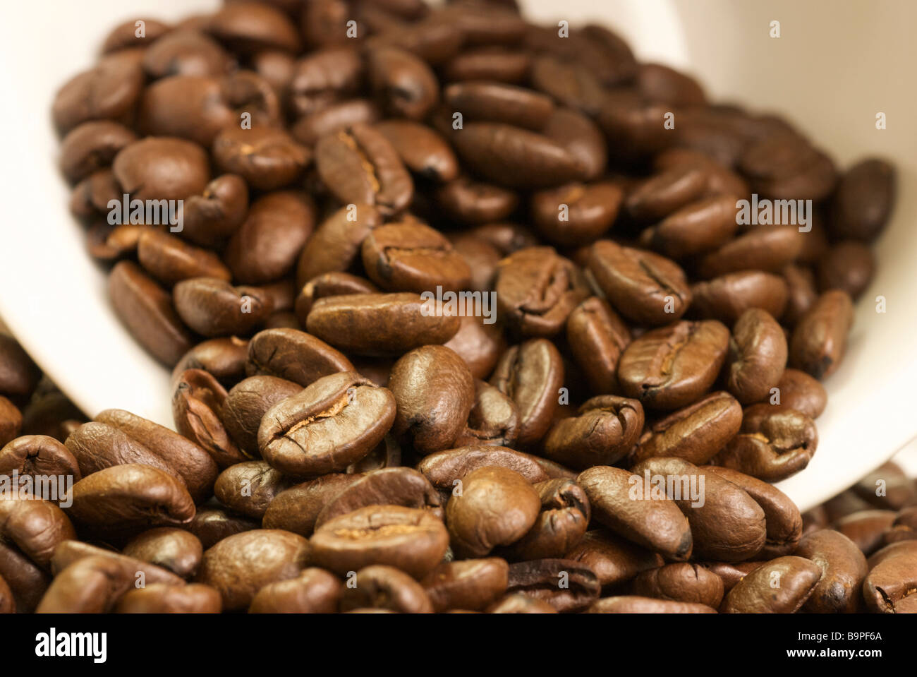 Coffee beans flowing out of a cup Stock Photo - Alamy