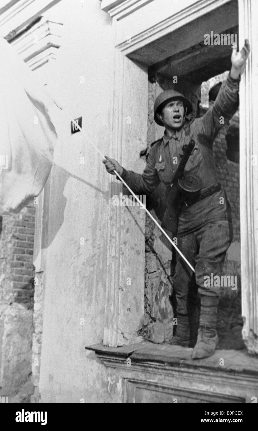 A Soviet soldier standing with a banner in a window opening in the ...