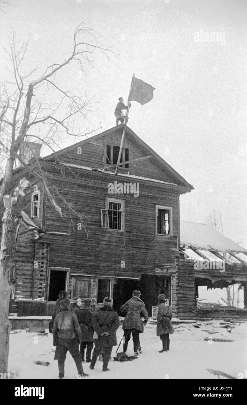 A Soviet soldier raising a flag on the roof of a house in liberated ...