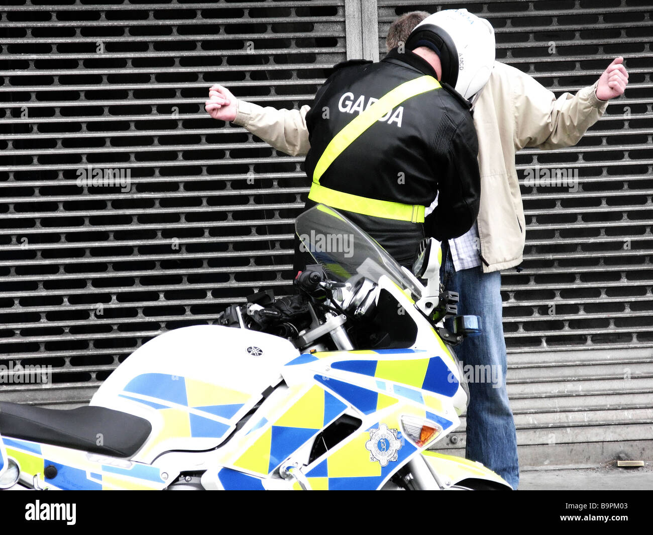 An Irish policeman Garda searches a suspect on the street Stock Photo ...