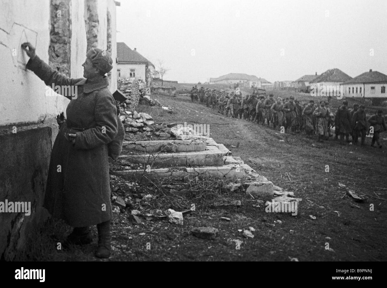 A Red Army man drawing a sign on the wall pointing the direction of the ...