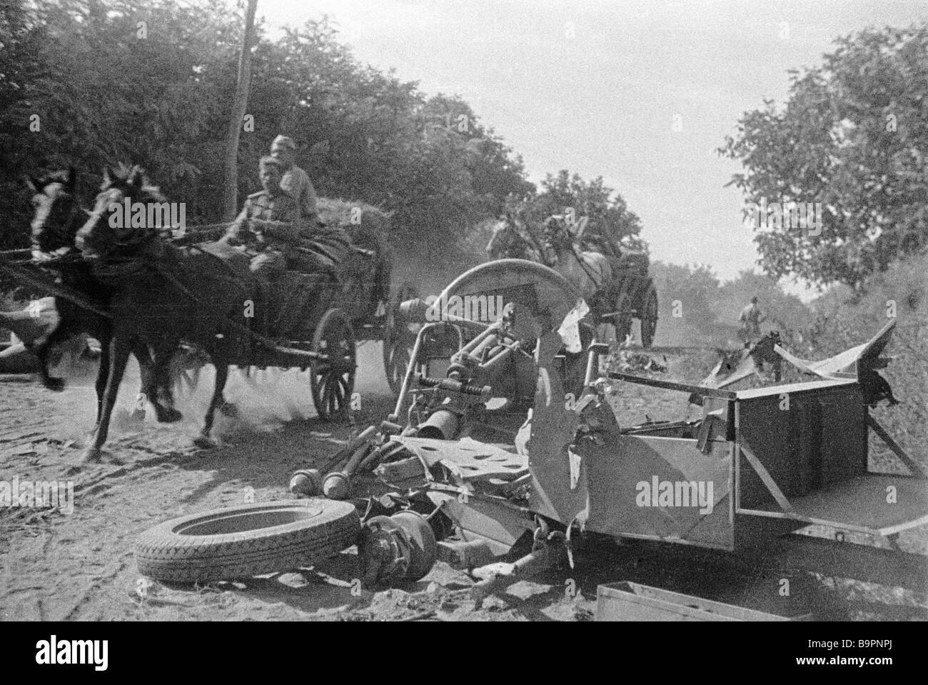 Carts driven by Red Army soldiers passing by remains of a vehicle Stock ...