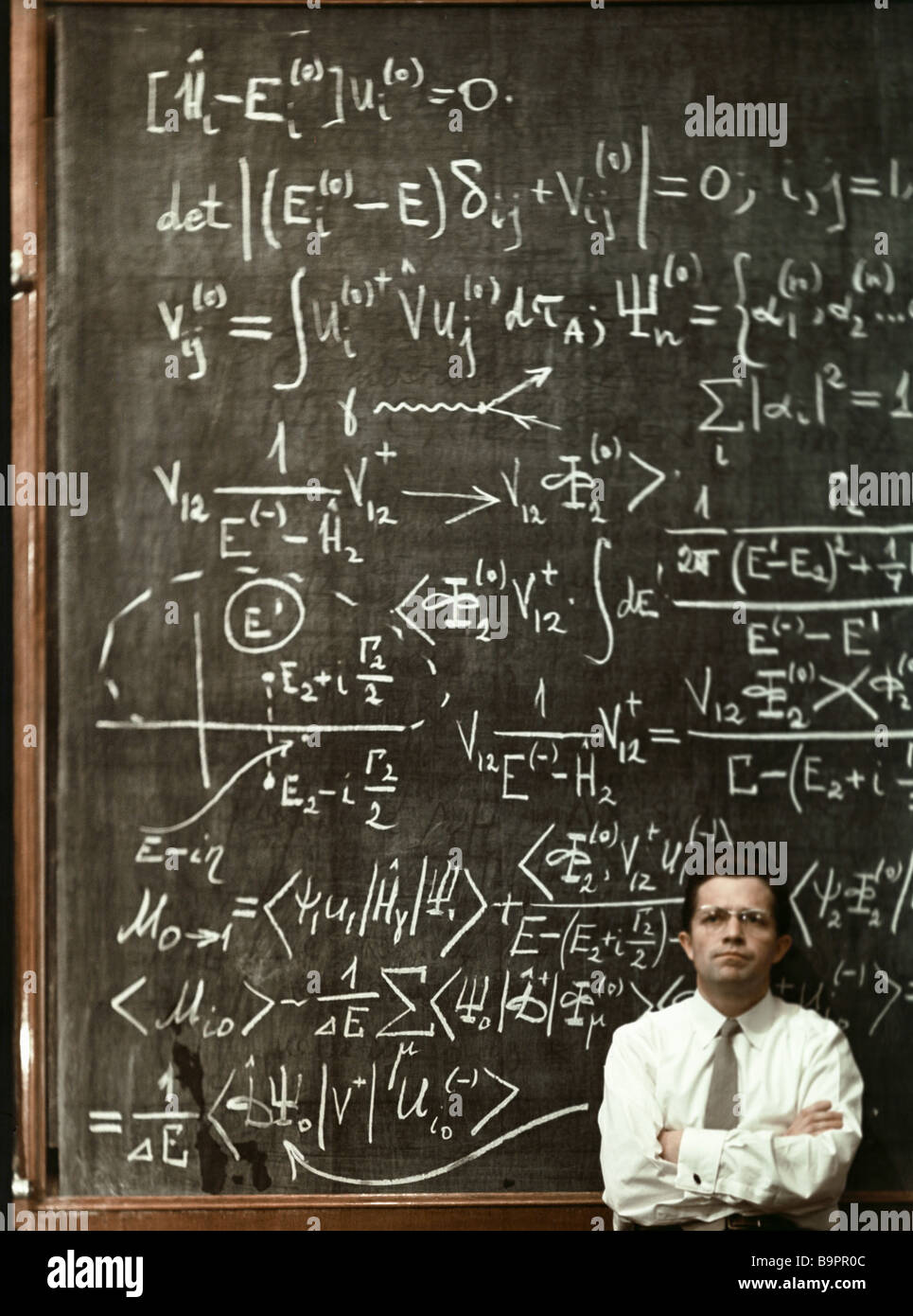 Scientist standing at blackboard with mathematical formulas written on ...