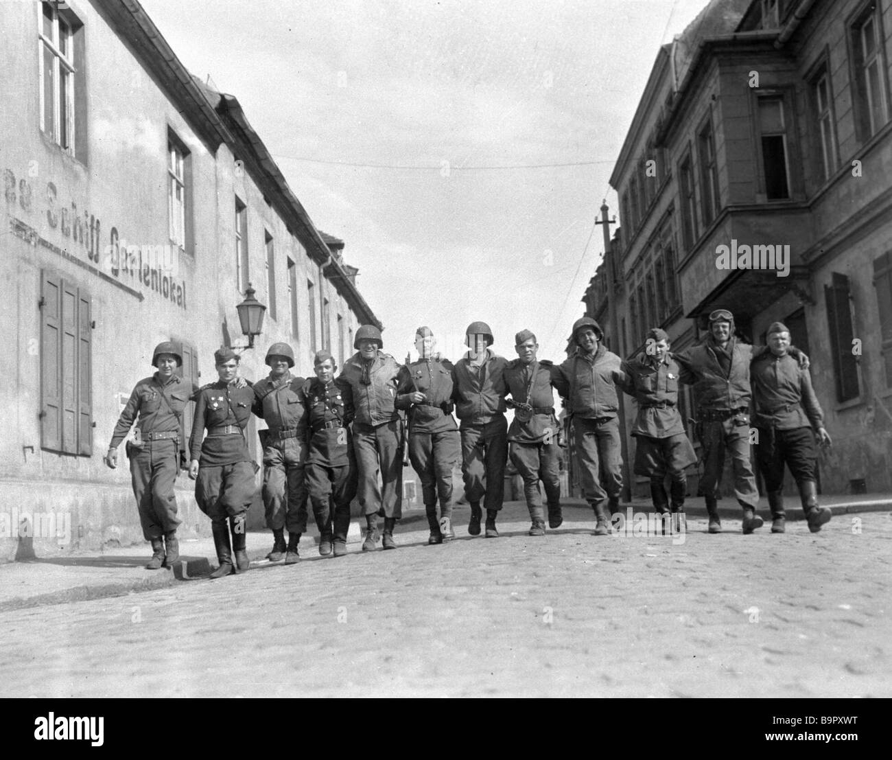 Soviet and American soldiers marching along the streets of Torgau ...