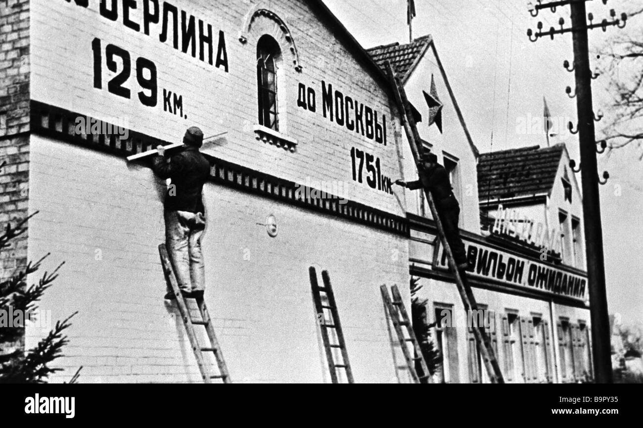 A Soviet soldier making a sign on an administrative building in a ...