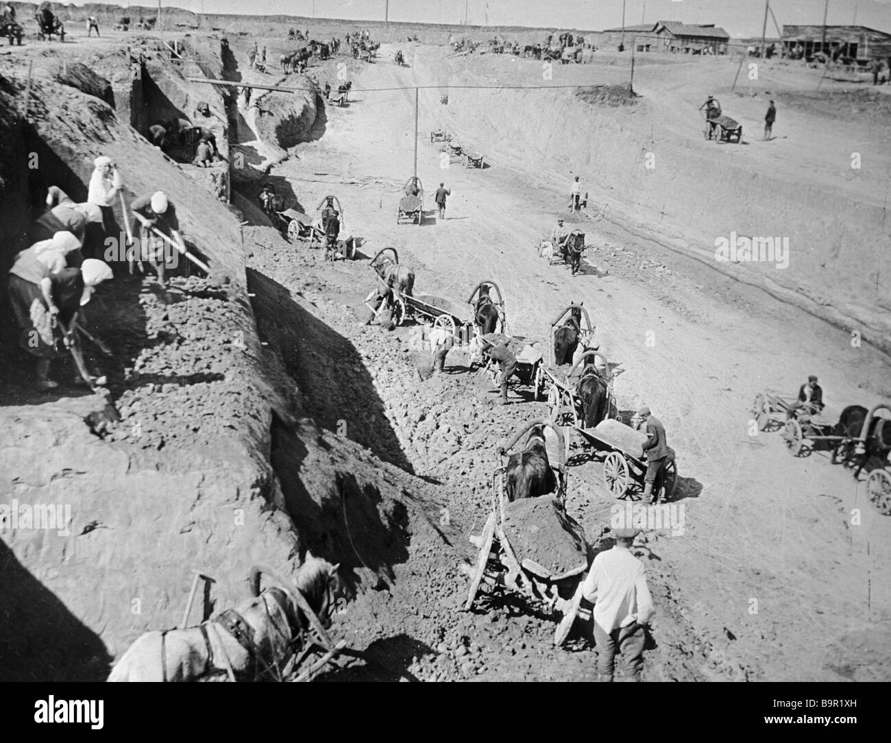 Workers remove soil from a foundation area for the future open hearth ...