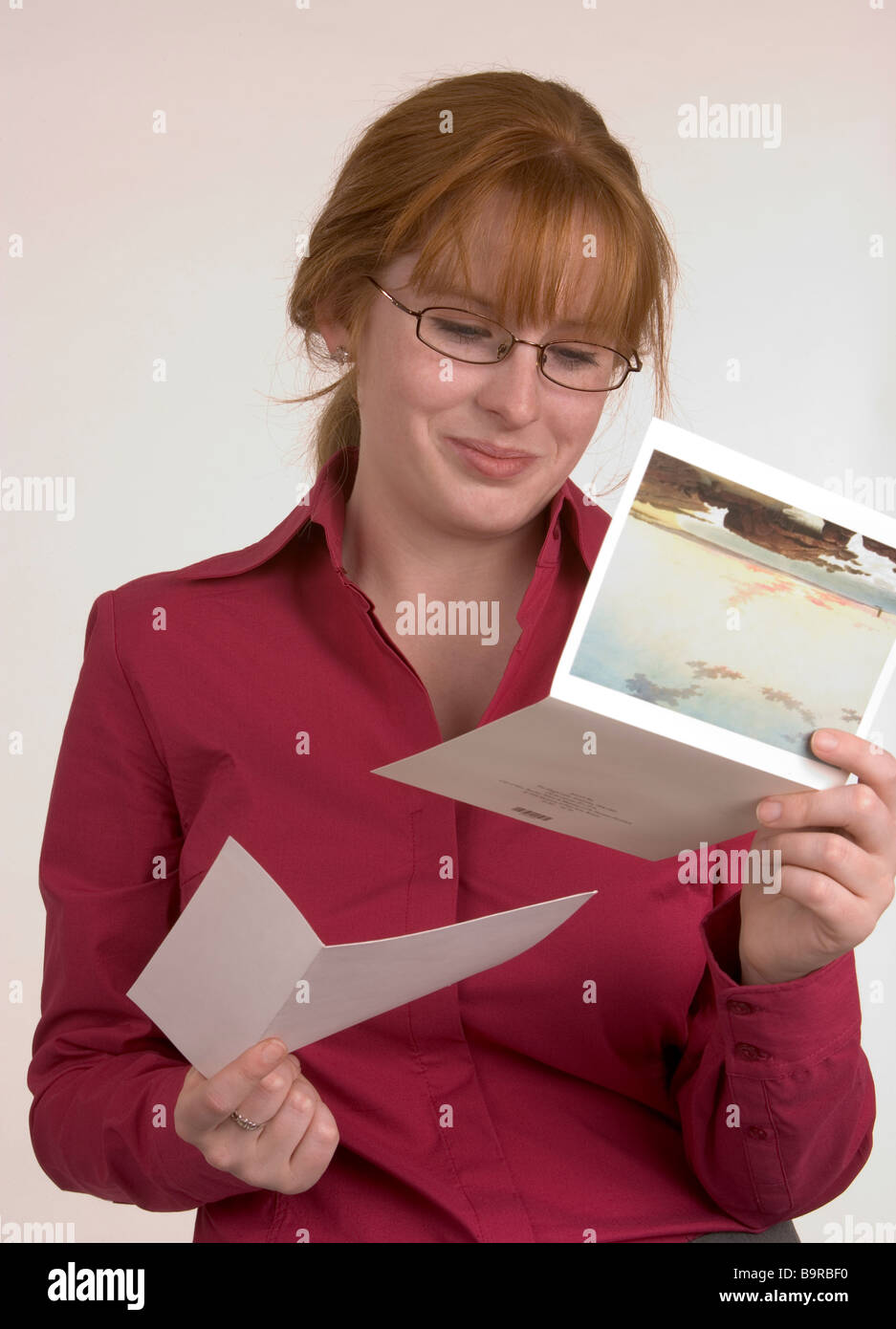 A woman reading a card that has conveyed some happy news that has made ...