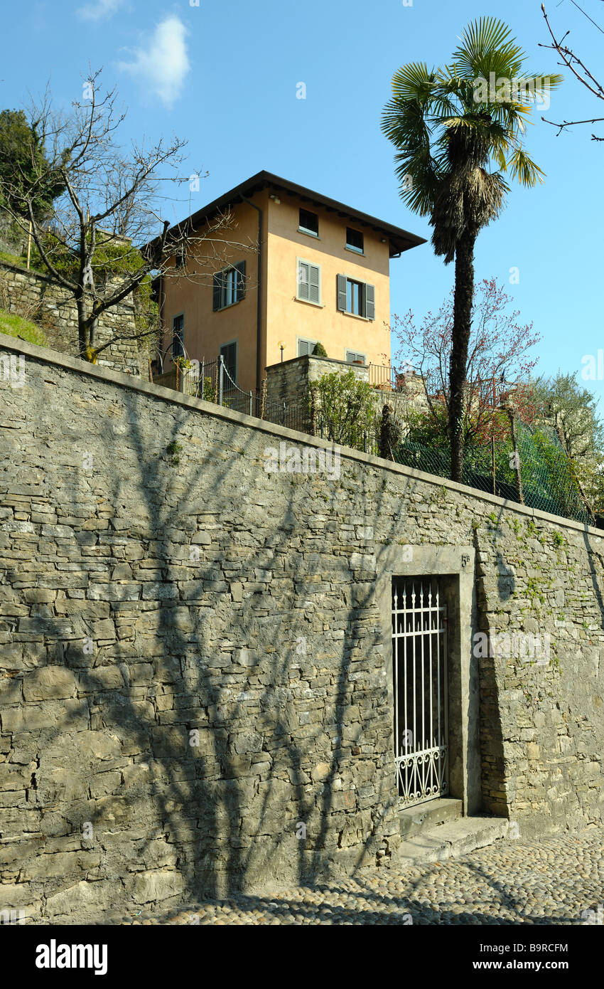 Northern Italian villa on a hill with a palm tree in its walled garden ...