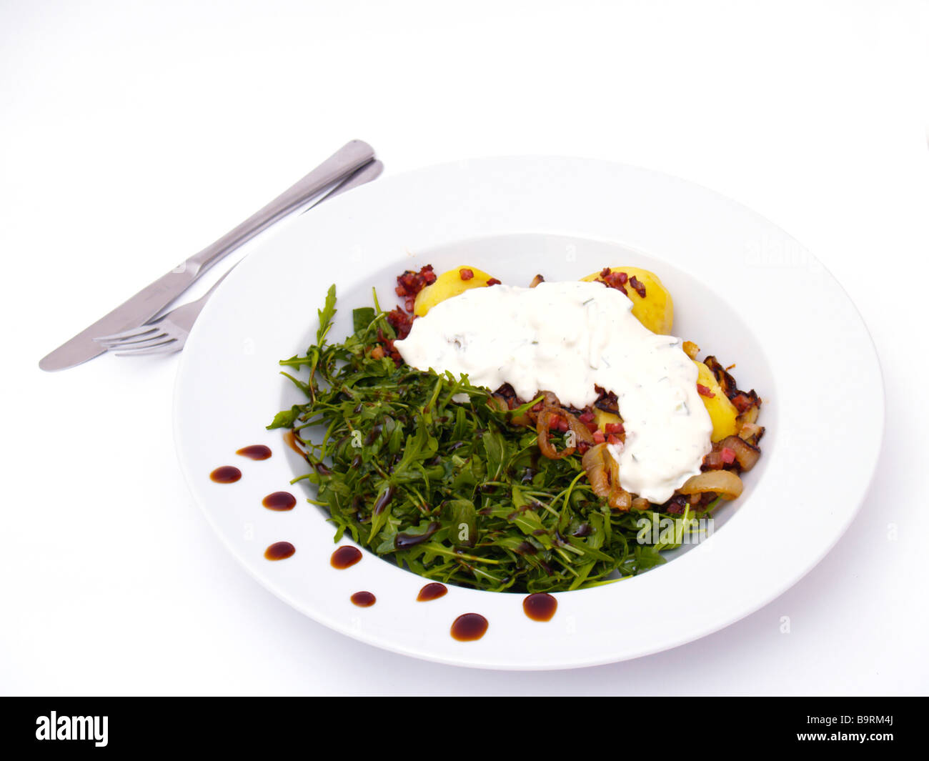 herbs flavoured curd and bacon on potatoes with arugola Stock Photo - Alamy