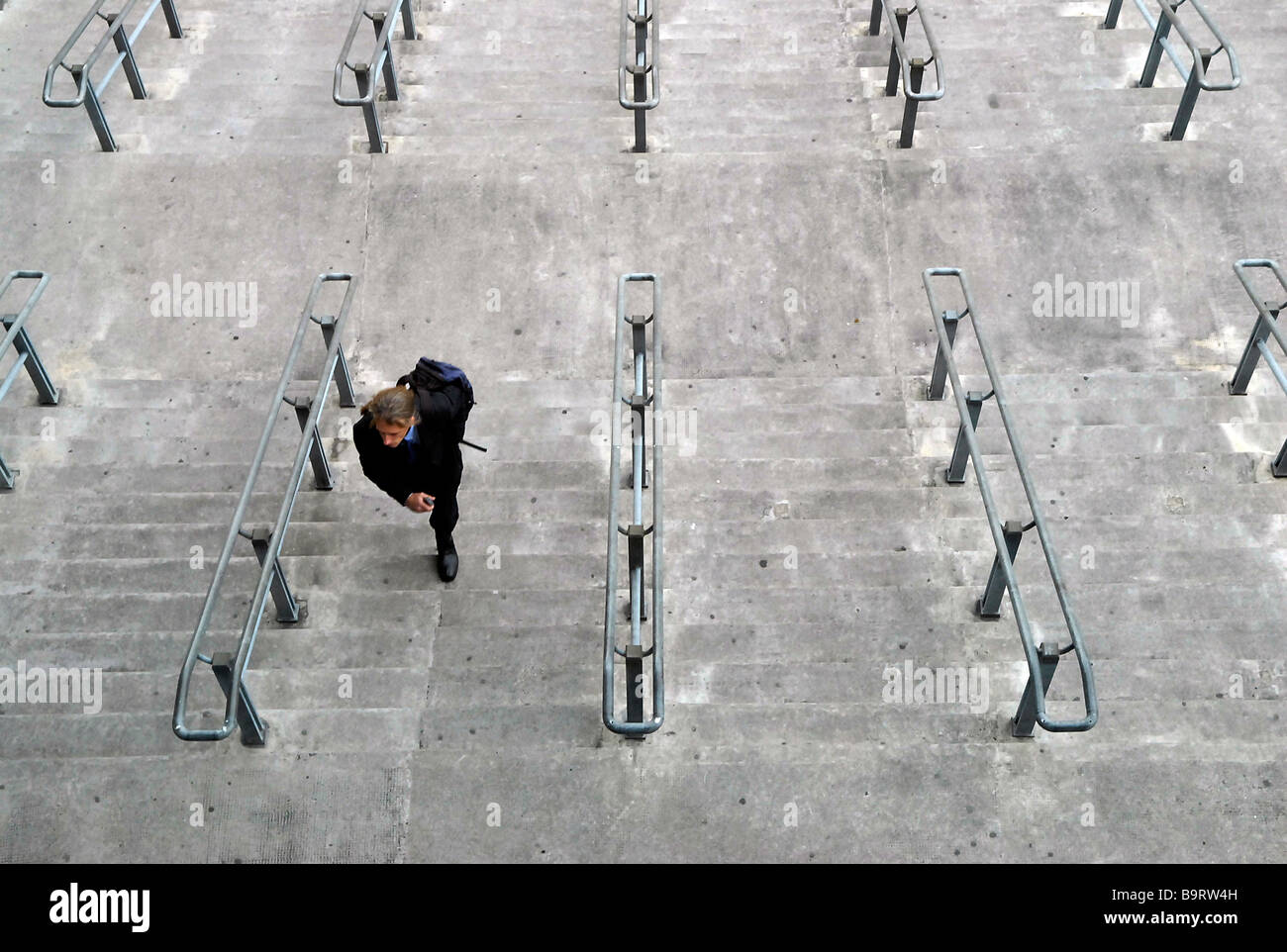 A man in a blue suit running up grey concrete steps Stock Photo - Alamy