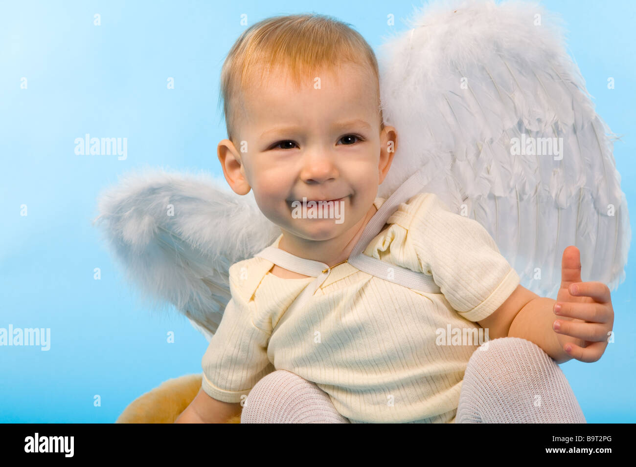 small merry boy dreessed as angel on blue background Stock Photo - Alamy