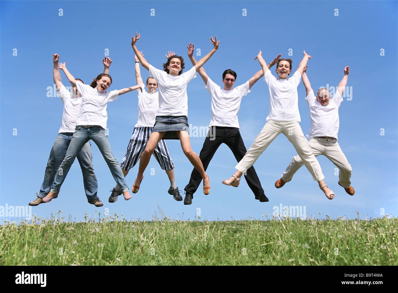 Seven friends in white T-shirts swing hands in a jump Stock Photo - Alamy