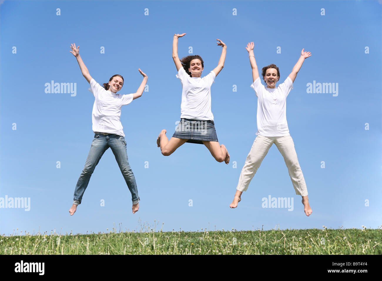 Three girlfriends in white T-shirts jump having waved hands Stock Photo ...
