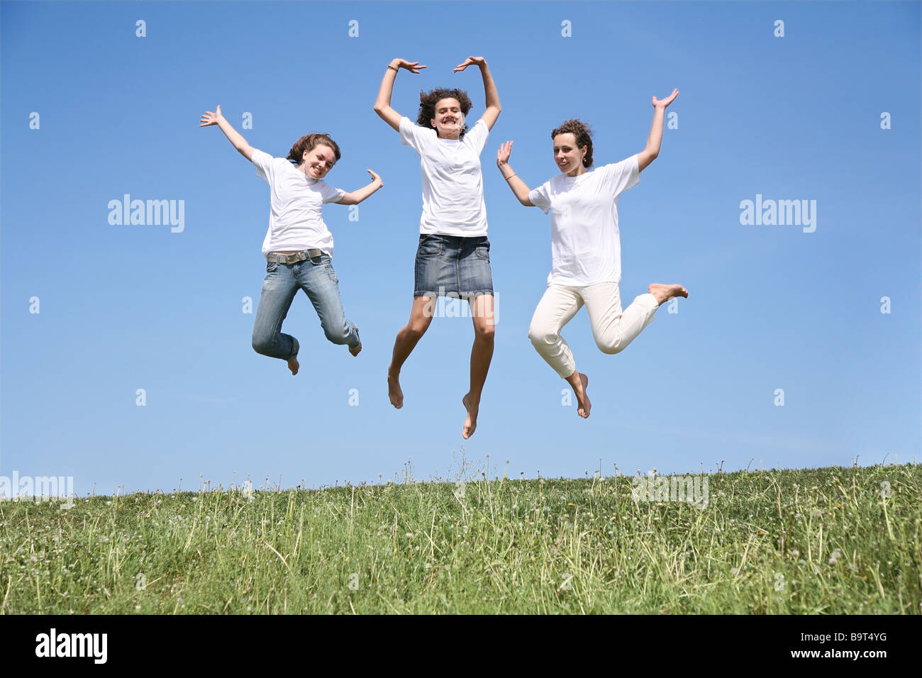 Three girlfriends in white T-shorts jump simultaneously Stock Photo - Alamy