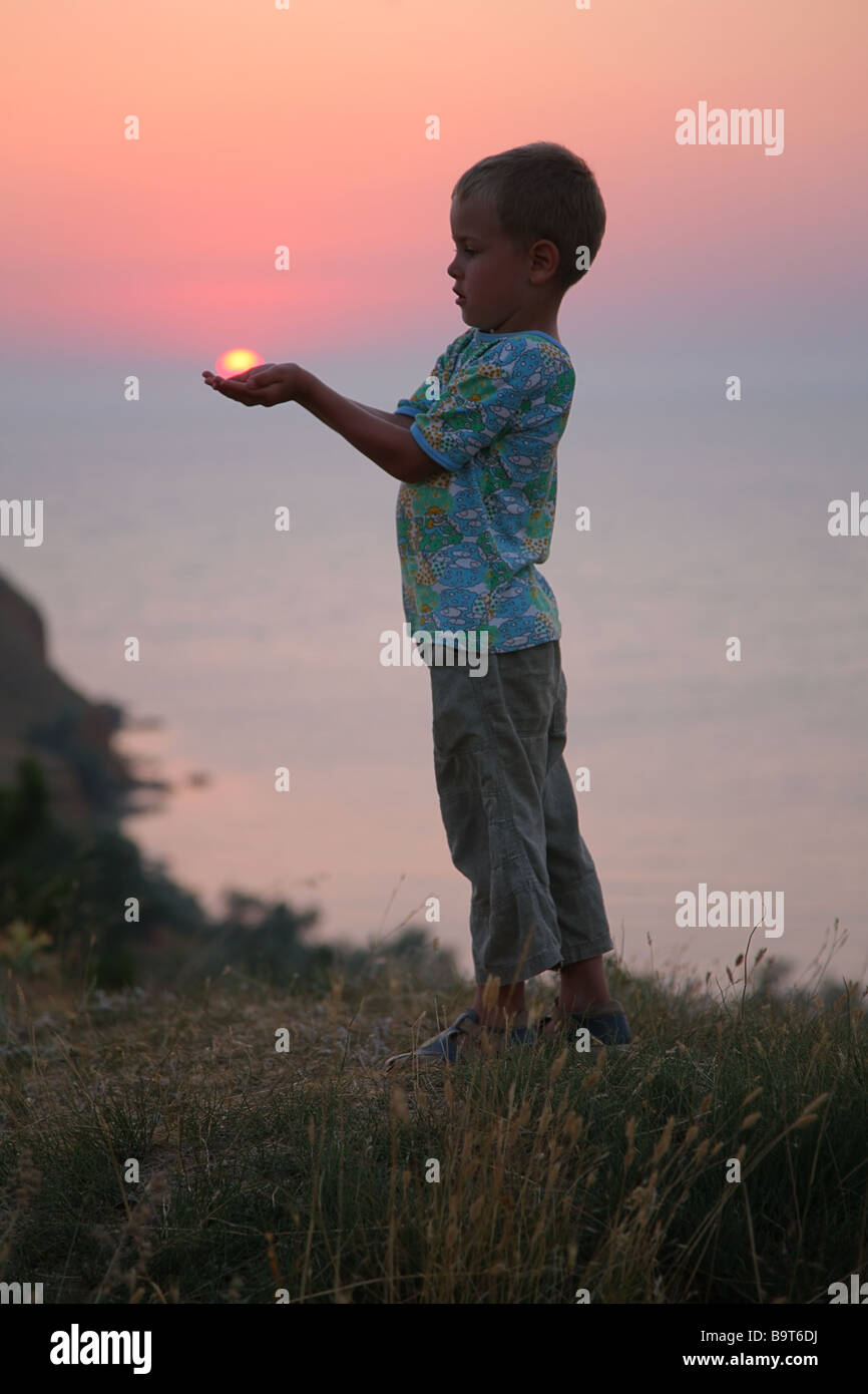 The boy holds the sun in hands Stock Photo - Alamy