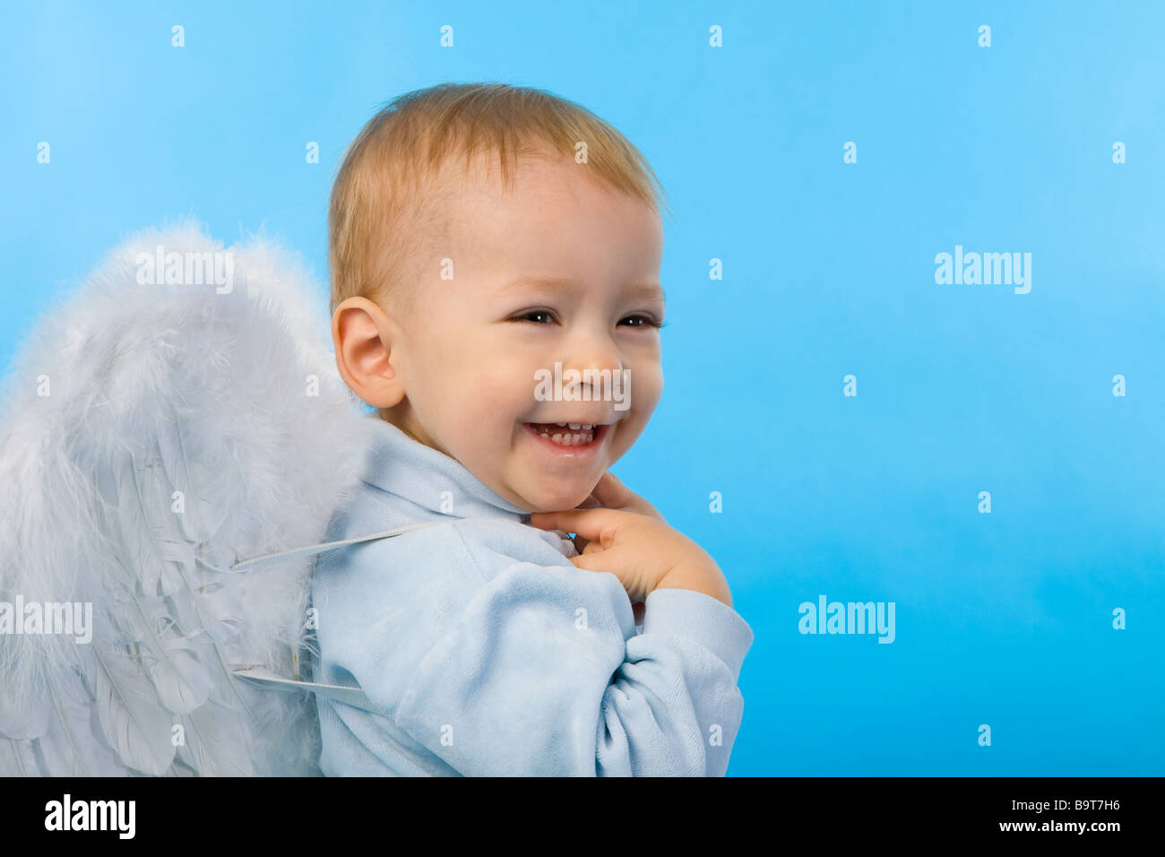 small merry boy dreessed as angel on blue background Stock Photo - Alamy