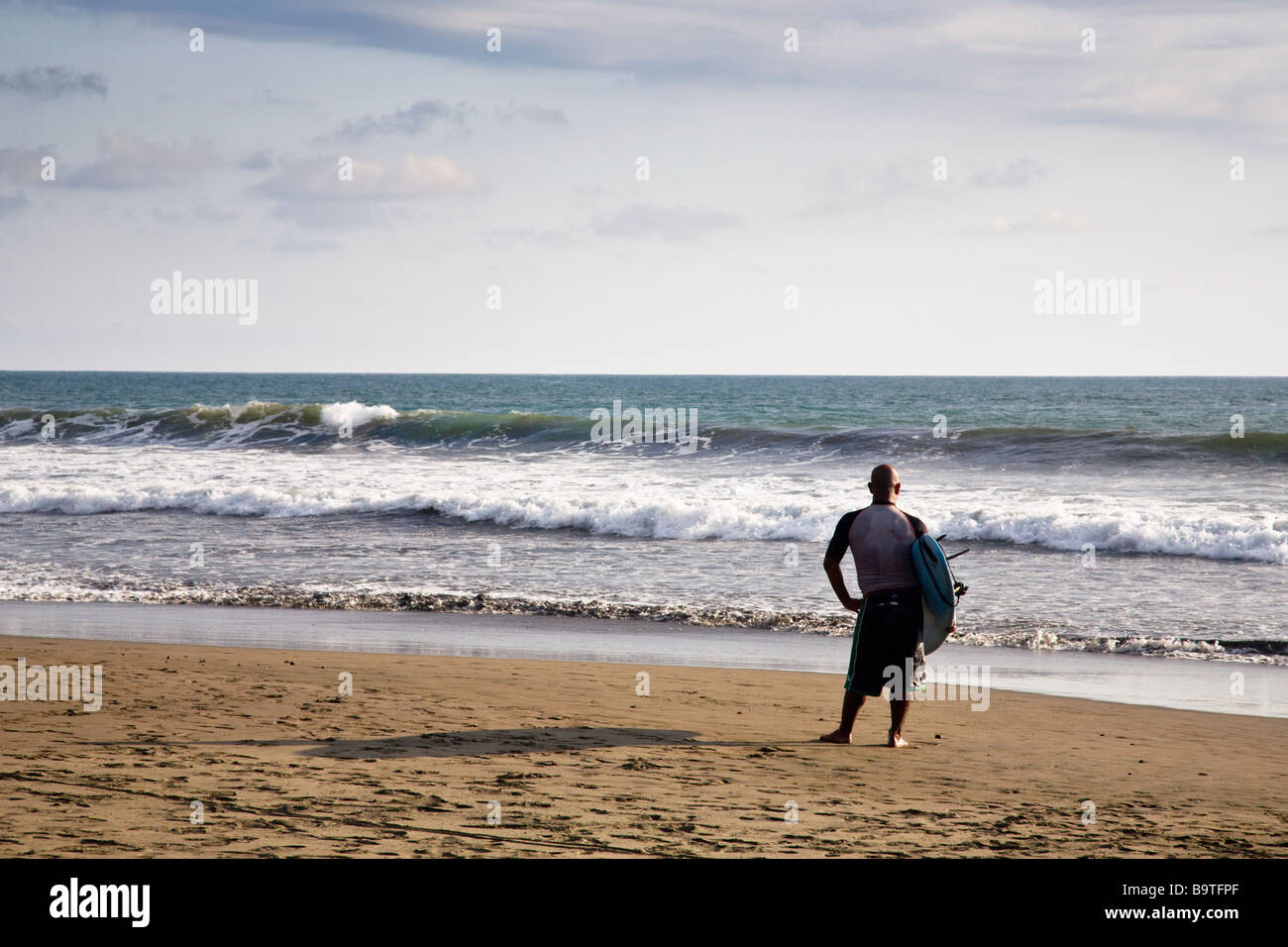 Surfer standing on the shore with his surfboard at Jaco Beach, Costa ...