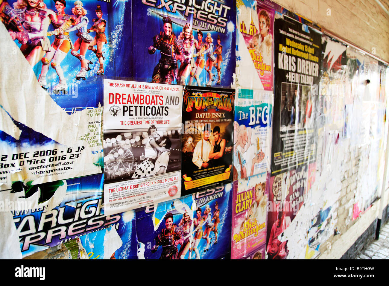 A narrow alleyway covered in theatre posters and advertising flyers ...
