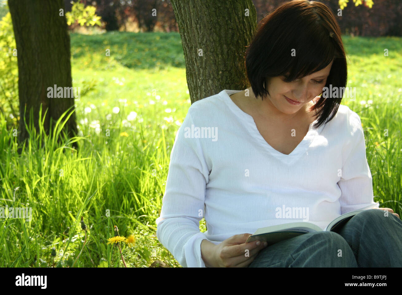 Student reading book in park Stock Photo - Alamy