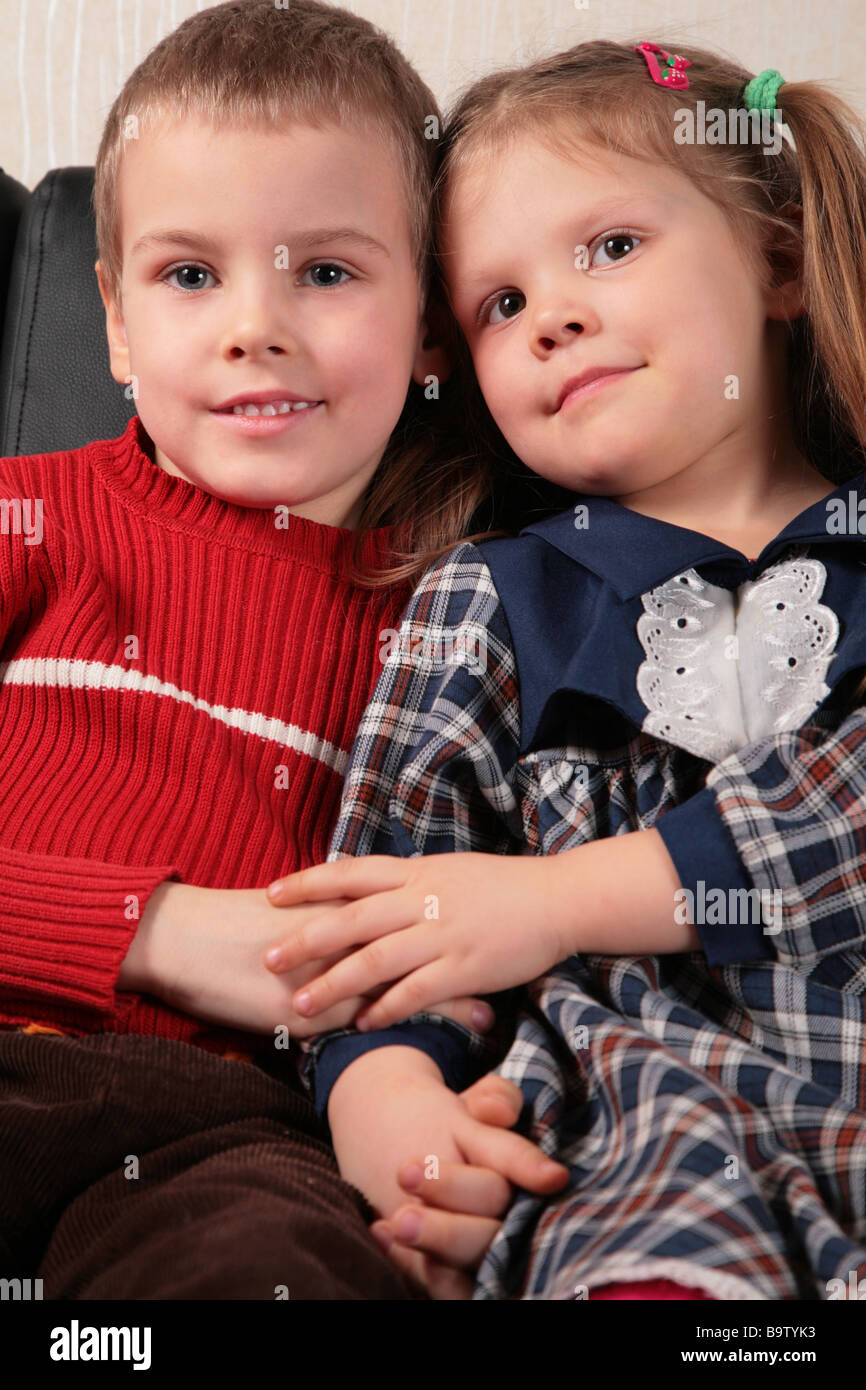 two children sit on sofa holding hands Stock Photo - Alamy