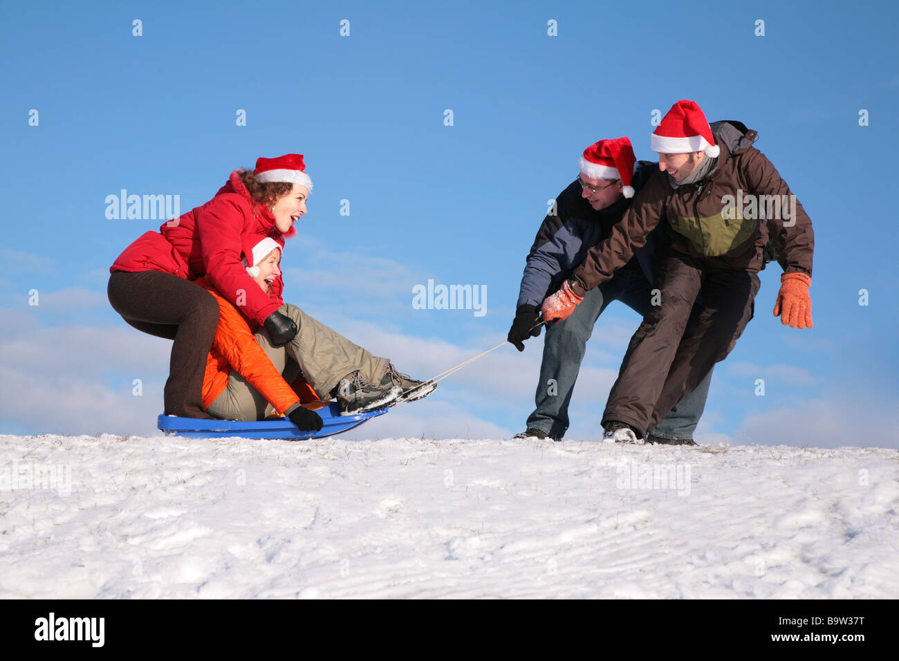two men pull two women on sled Stock Photo - Alamy
