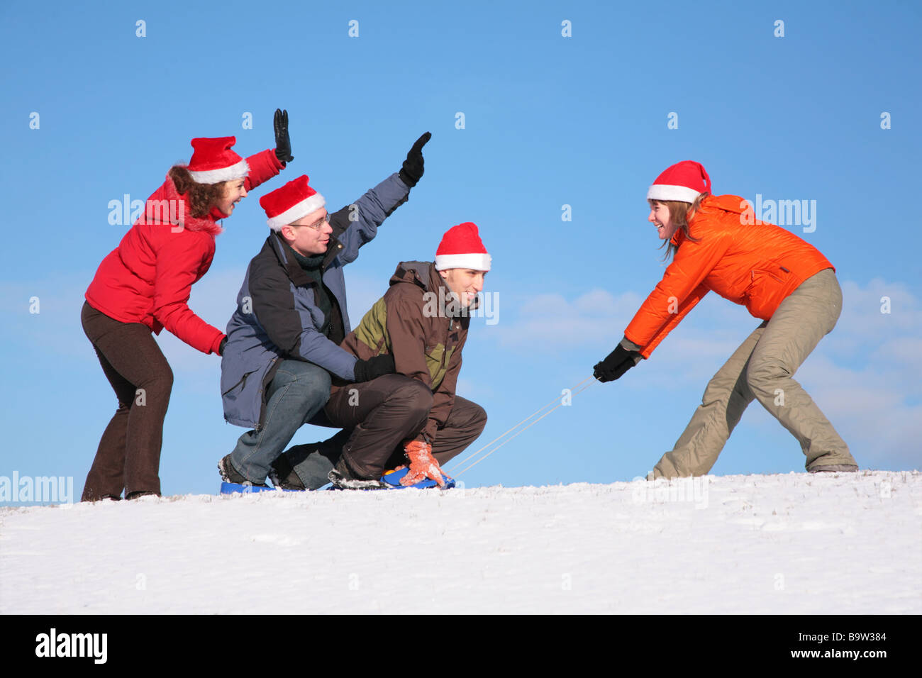 one woman pull two men on sled, other woman push them 2 Stock Photo - Alamy
